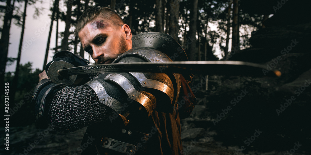 mystery scarface knight in armor with sword and crossbow in the forest ...