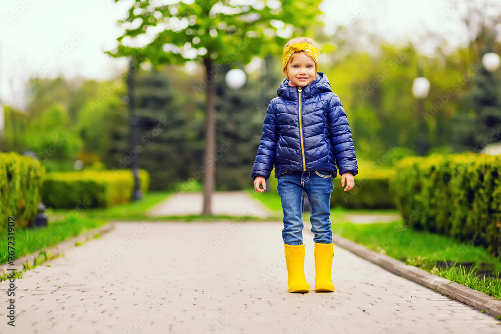 Little girl playing after the rain in the park. A cute children girl ...