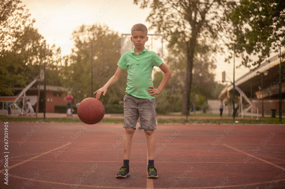 one boy with a serious face expression, dribbling ball on a basketball ...