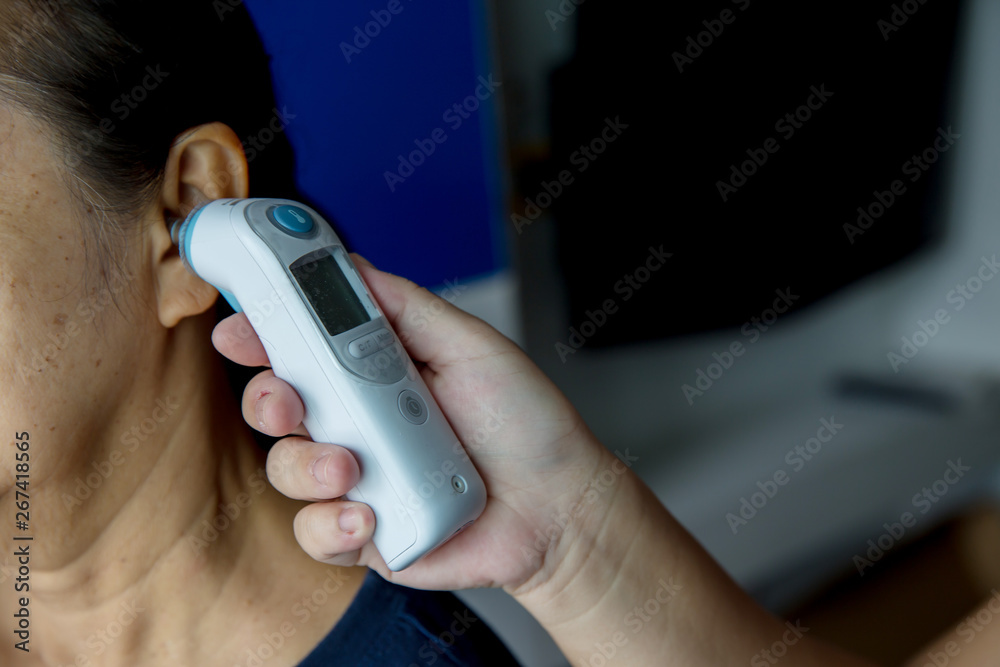 Doctor checking patient's temperature in the ear with Tympanic ...