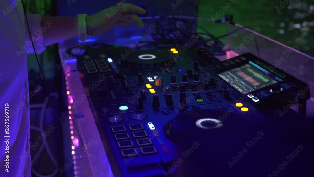 DJ controller and music console in colorful light at dance party in ...