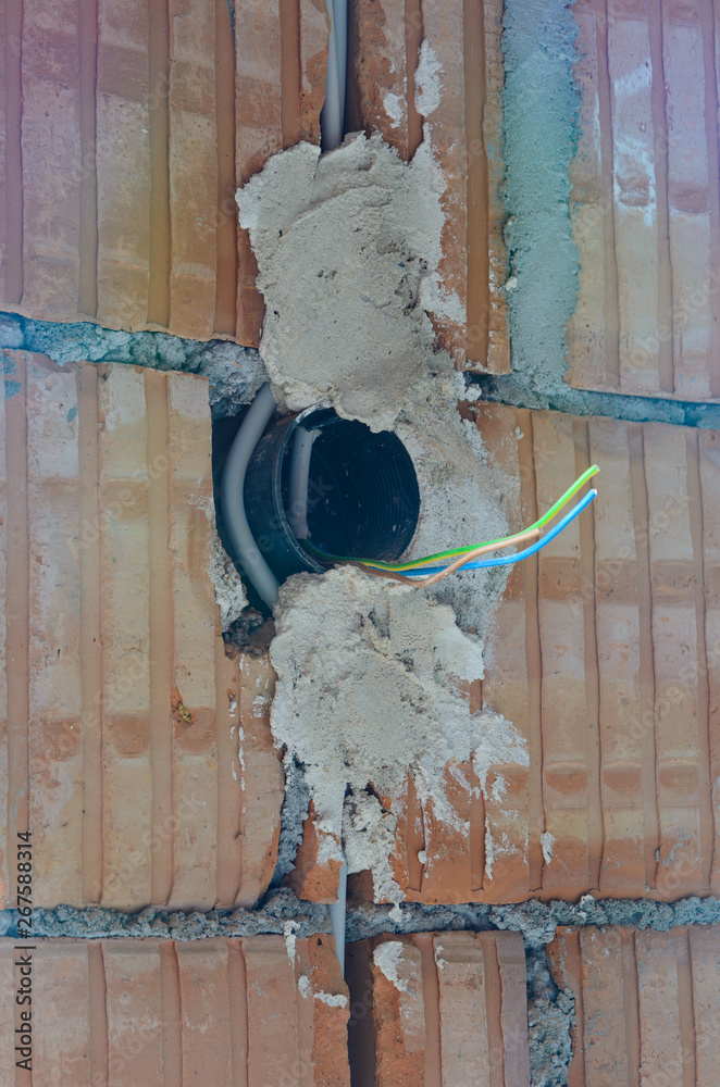 Electricity wire instalation in brick wall, construction site interior ...
