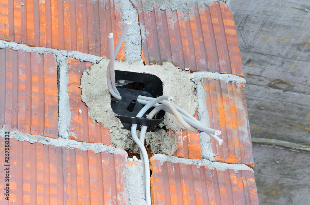 Electricity wire instalation in brick wall, construction site interior ...