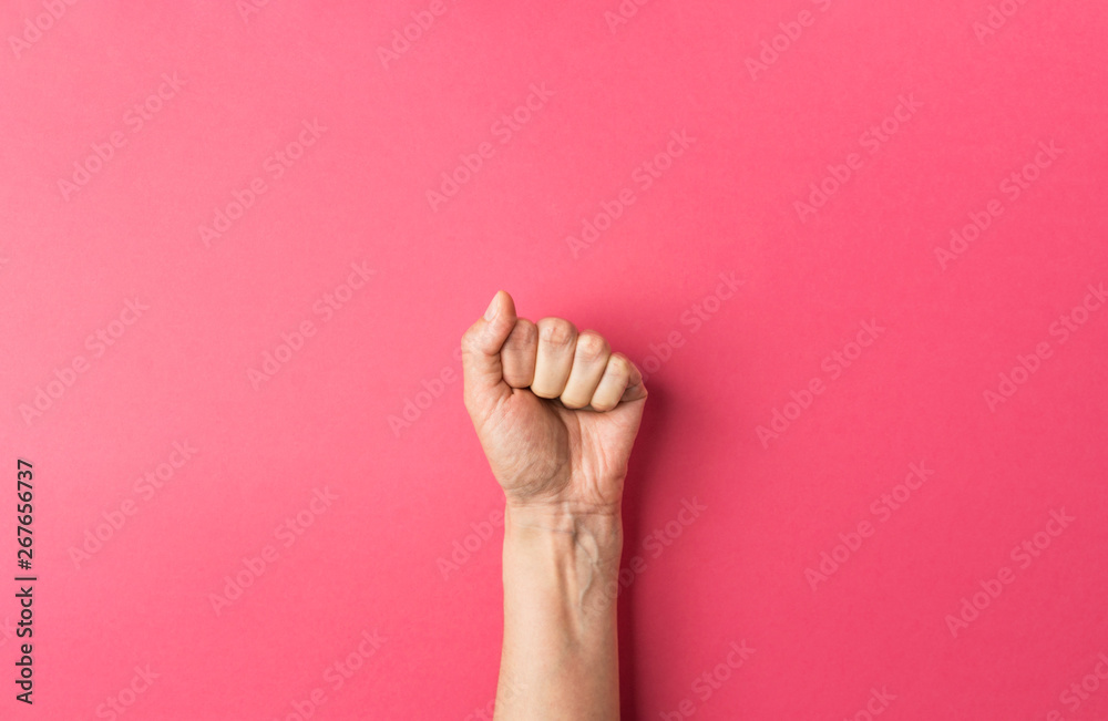 Young caucasian woman's hand with clenched fist on fuchsia pink ...