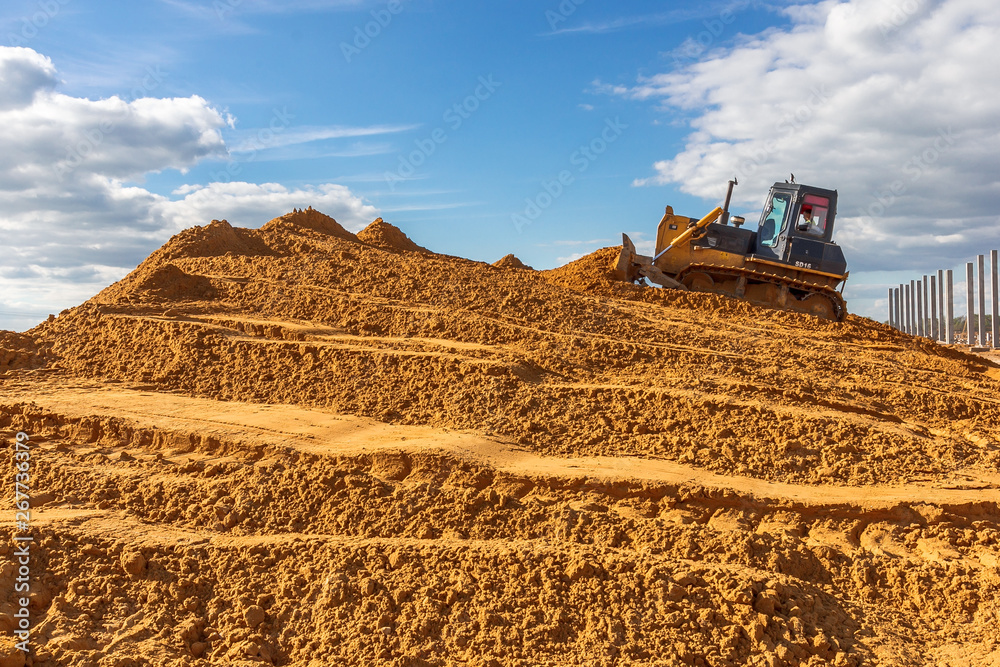 the bulldozer conducts earthworks at the construction site, rakes a ...