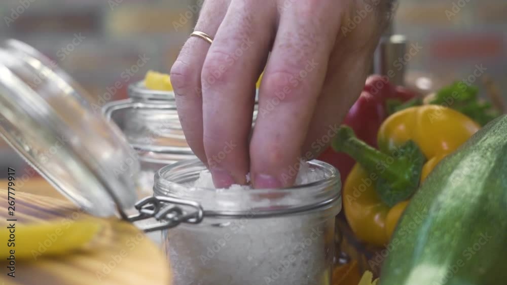 Close up chef cook hand taking salt pinch for salting food while ...