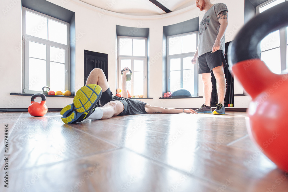 Healthy muscular strong man is engaged with kettlebells in the gym. The ...