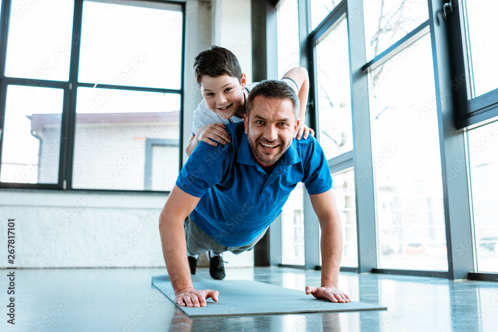 happy father doing push up exercise with son on back at gym Stock Photo ...