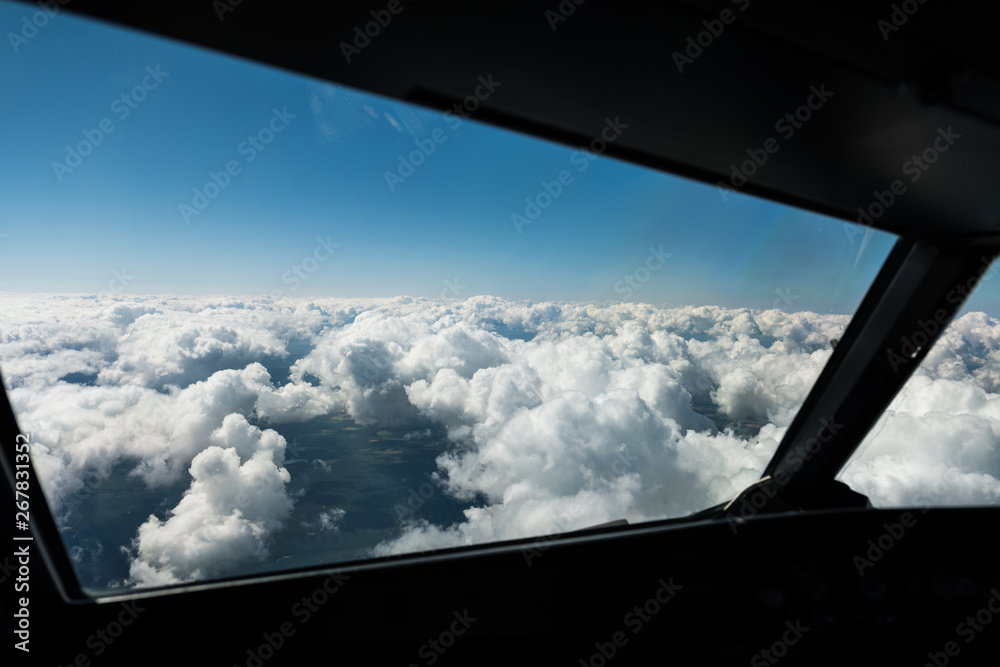 Pilots view out of the cockpit window toward clouds and blue sky above ...