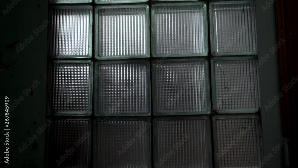 Close-up of Glass bricks pattern window in a dark room with reflection ...