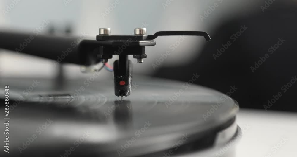 Needle and arm on spinning vinyl record turntable player, closeup side ...