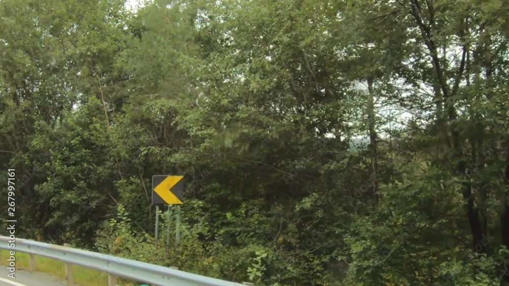 High speed route on a road with green forests on both sides and through ...
