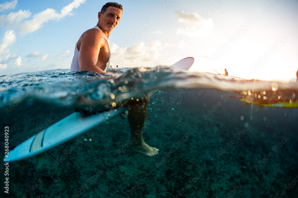 Adult male surfer sits on his board and looks at the camera Stock Photo ...