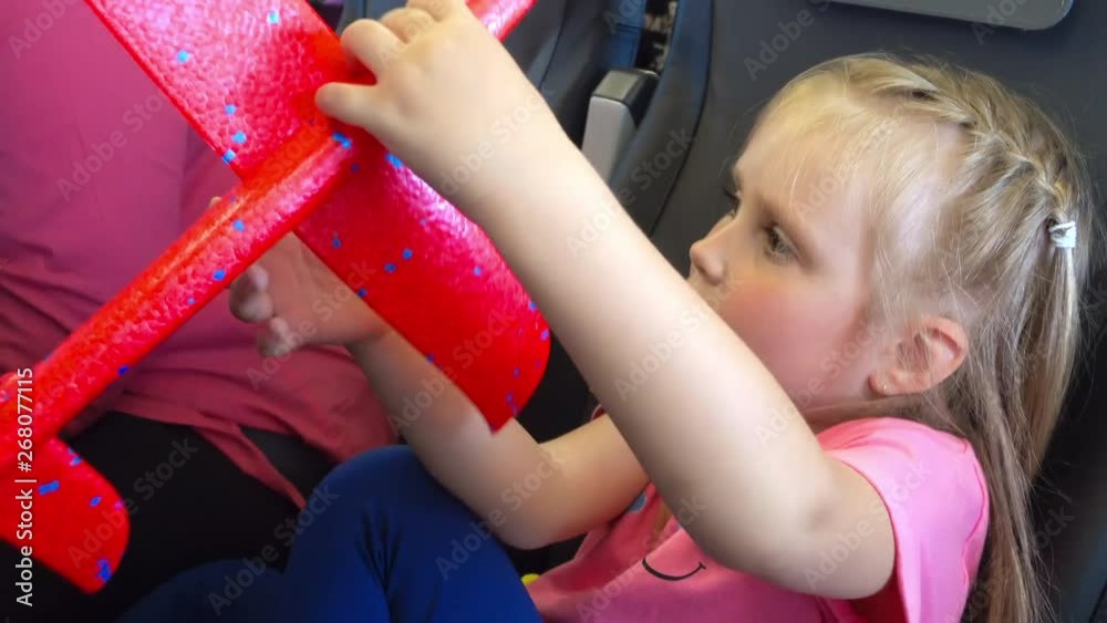 Little blond girl plays in flight with a red airplane. Flight of a ...
