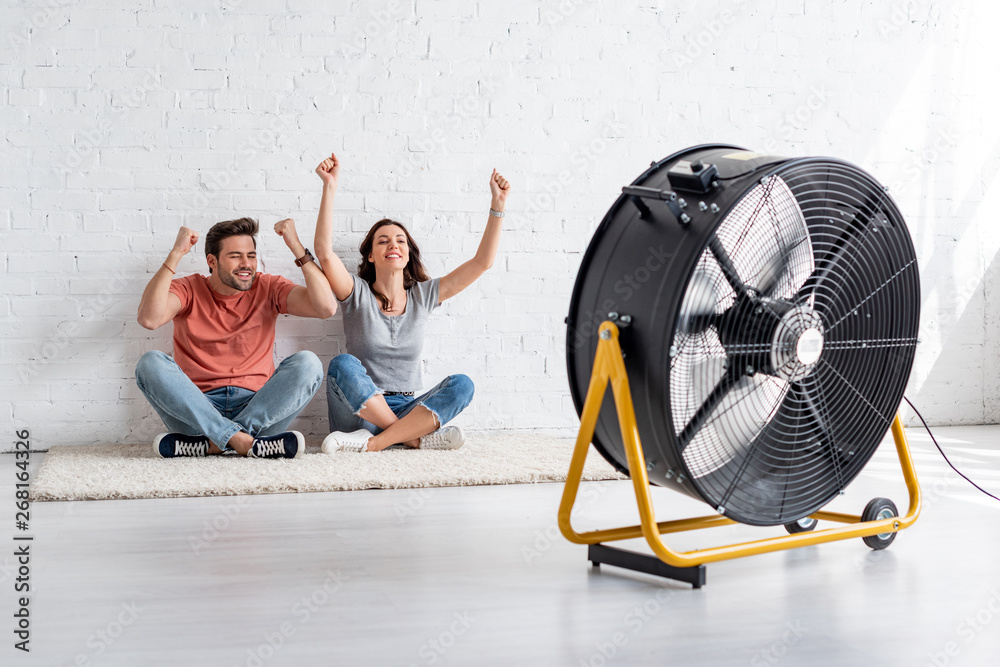 excited man and woman sitting on floor by white wall in front of ...