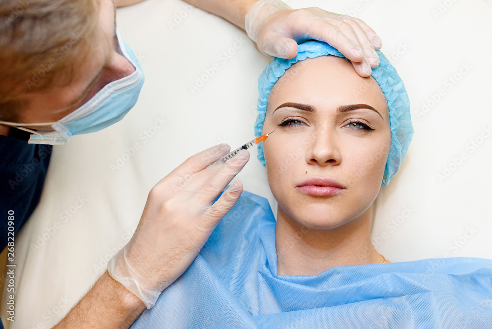 Woman makes botox injections in eye corner. Doctor cleans the girl's ...