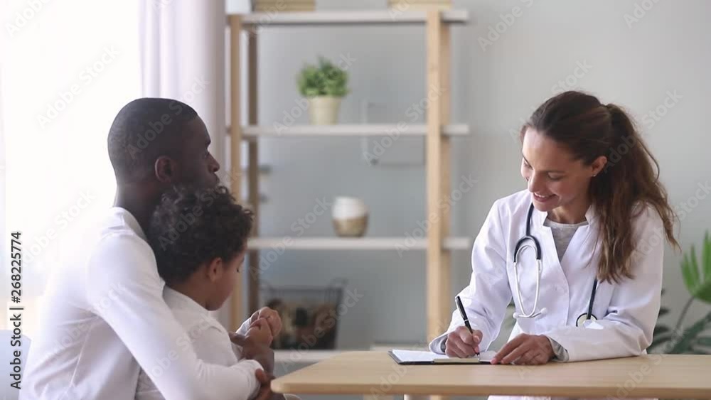 Female caucasian doctor listening to african father of little patient ...