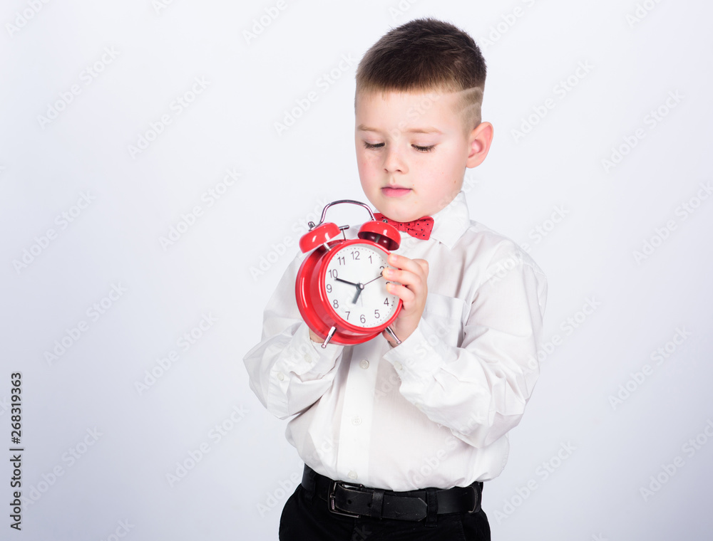 Set up alarm clock. Child little boy hold red clock. It is time ...