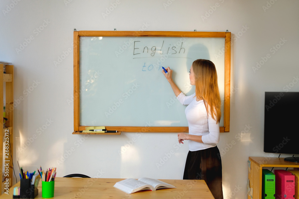 Female teacher writing on the marker board im classroom. Education ...