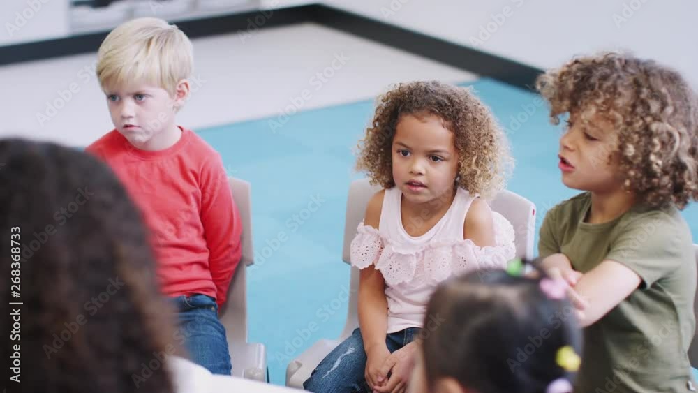 Vidéo Stock Infant school kids sitting on chairs in classroom listening ...