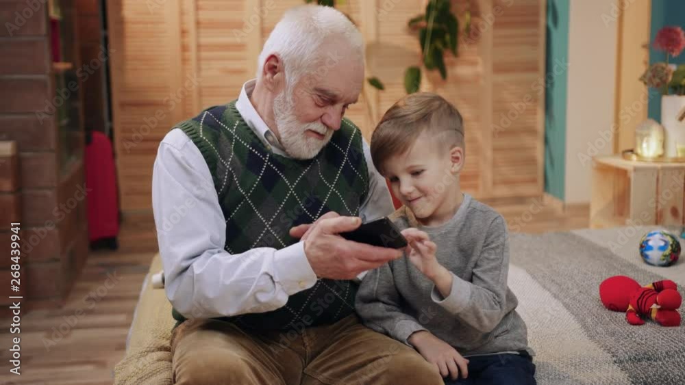Vidéo Stock Grandfather and grandson use smart phone at home smiling ...