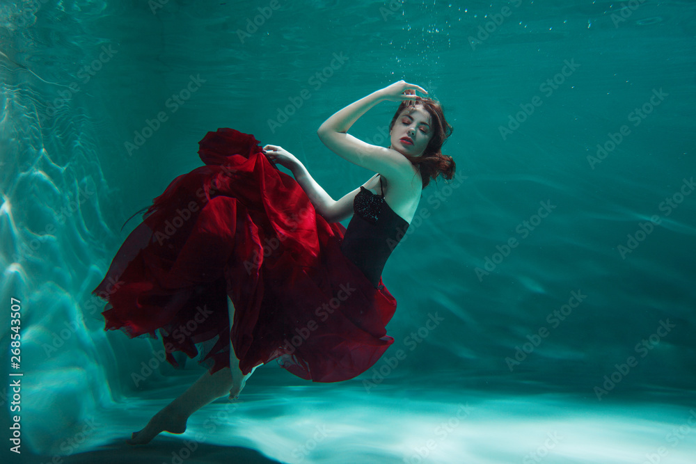 beautiful girl in a red dress swims under water Stock Photo | Adobe Stock