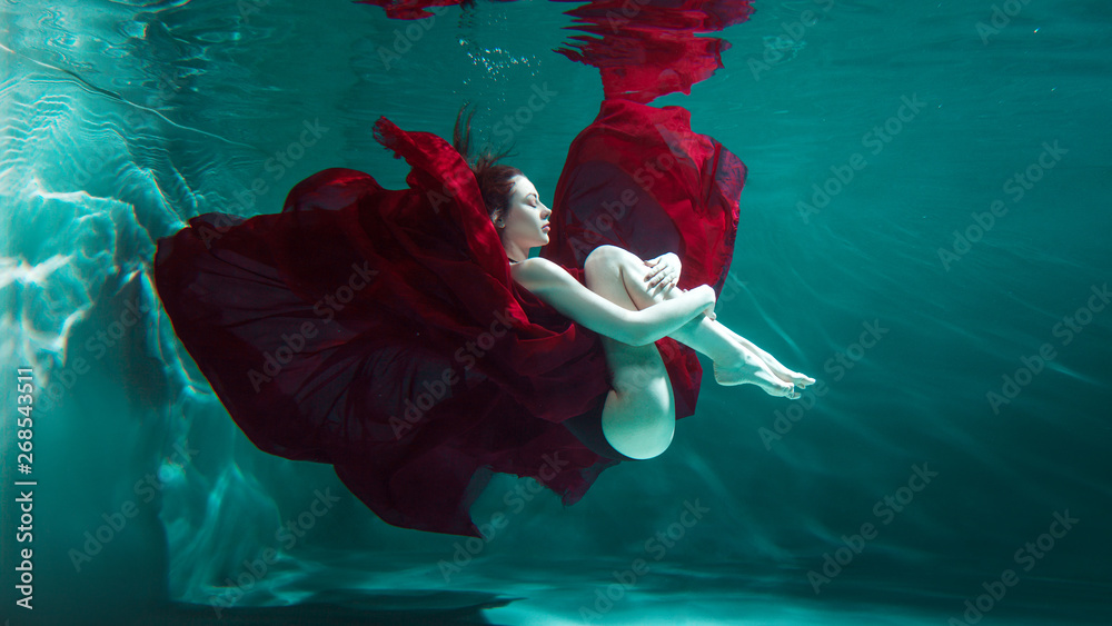 beautiful girl in a red dress dive into the water. Stock Photo | Adobe ...