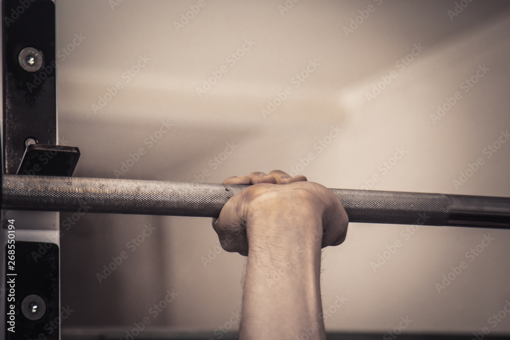 athlete with big hands holding a barbell bar in the training center ...