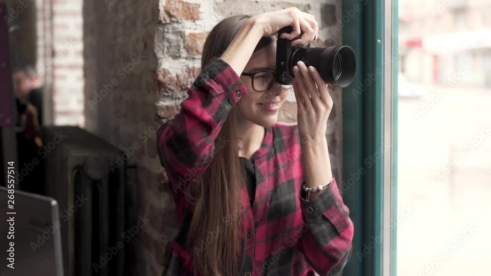 Stunning young lady sits on window sill in cafe and uses her camera ...