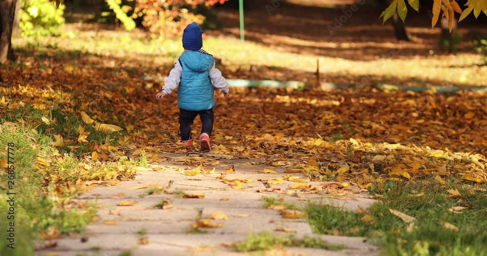 Back view footage of unrecognizable baby boy in blue hat and vest ...