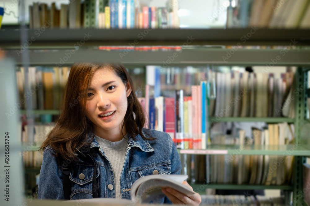 Asian Student searching for textbook in the bookshelf in the ...