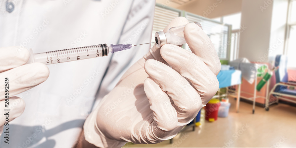 Doctor hand holding vials medication and injection needle with a ...