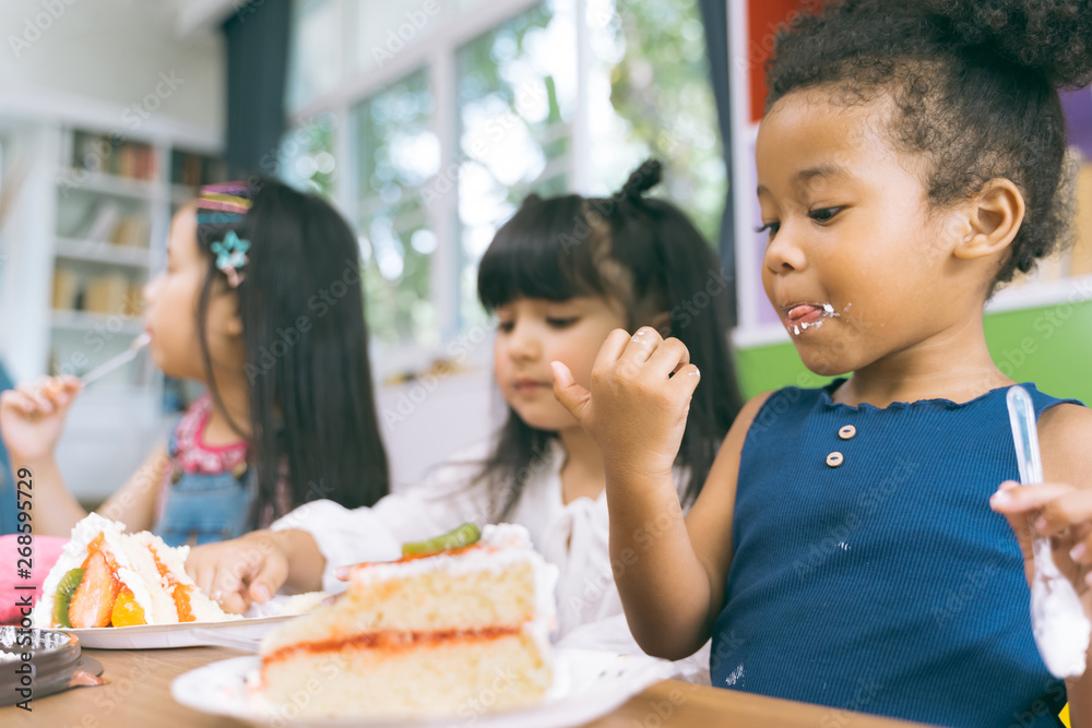 cute little child girl with diversity friends eating cake together ...