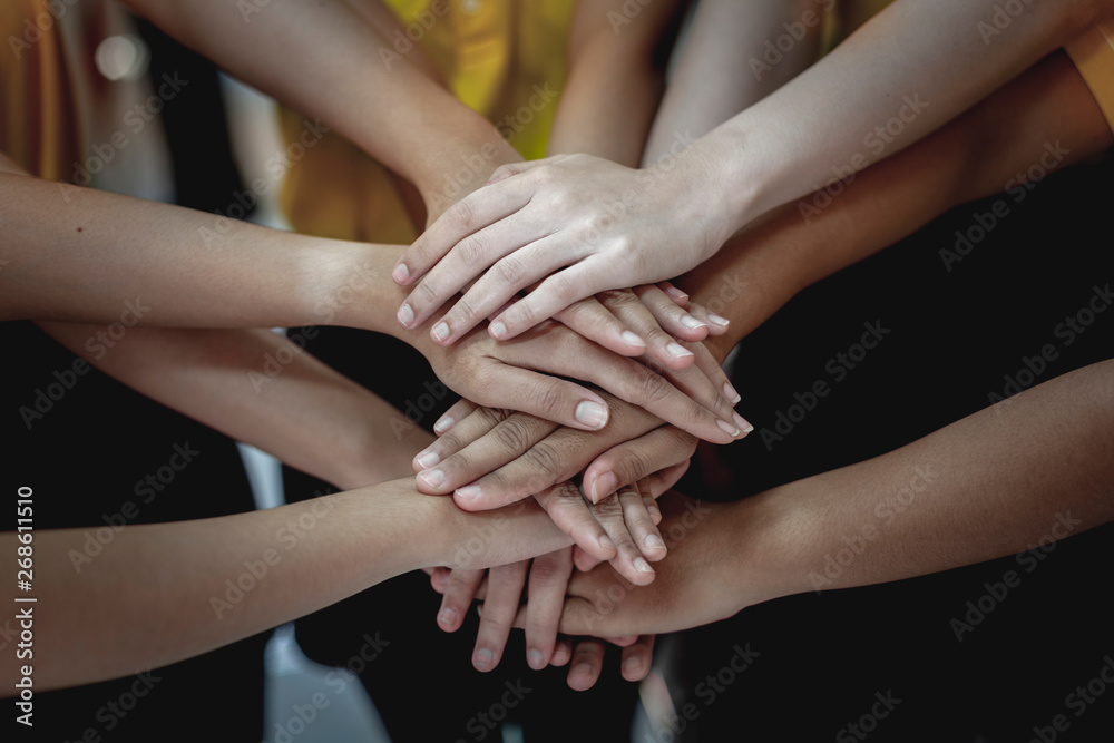 diverse people join hands in team building. activity men and women put ...
