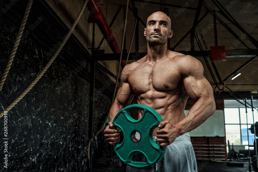Young handsome athlete, bodybuilder, weightlifter with a perfect body ...