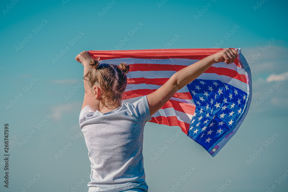 American flag. Back view little patriotic happy girl holding an ...