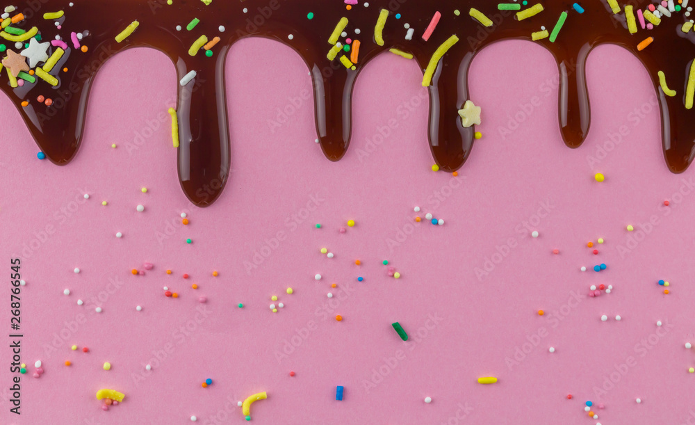Chocolate cake topping sprinkles with chocolate flowing down on pink ...