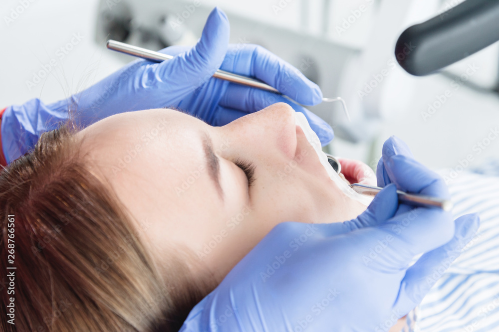 A close-up of the girl's face is examined by a dental examiner with his ...