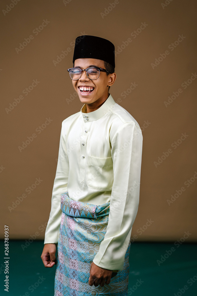 Studio portrait of a young Malay Asian man in a baju melayu, sampin and ...