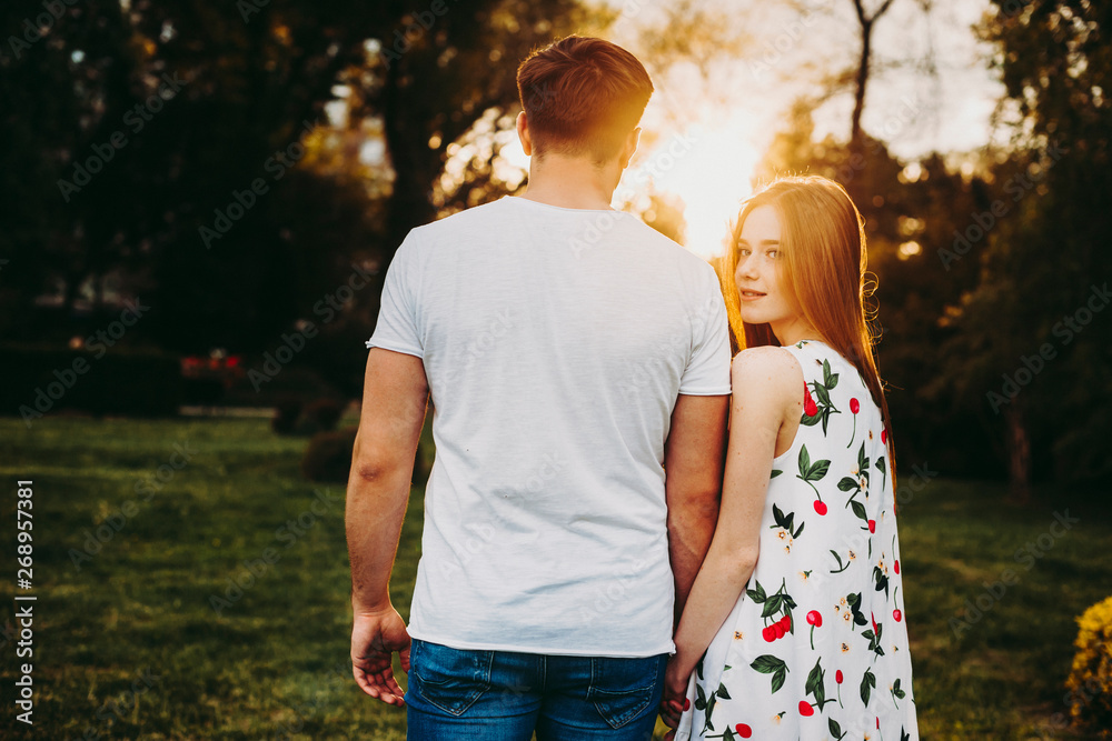 Back view of a caucasian couple dating outside against sunset while ...