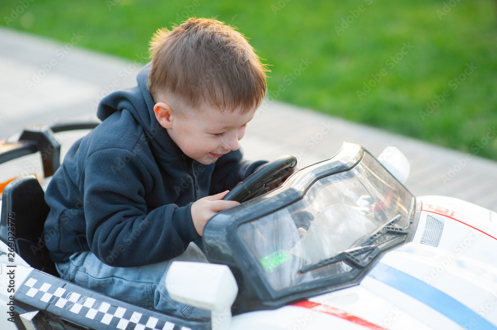 Cute little boy driving mechanical toy car turning the steering wheel ...