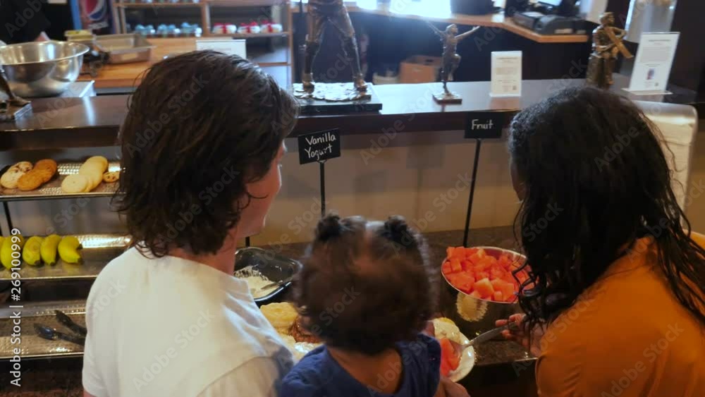 family with baby serve food from buffet line. A young multi-racial ...