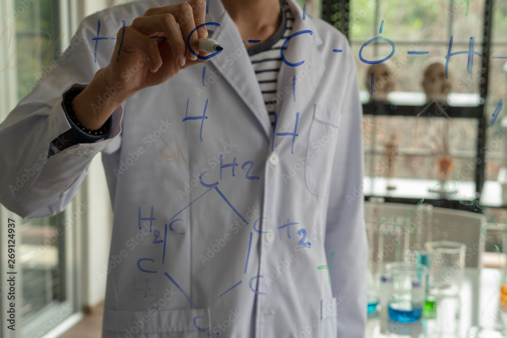 Scientists are writing a chemical formula with a blue whiteboard pen on ...