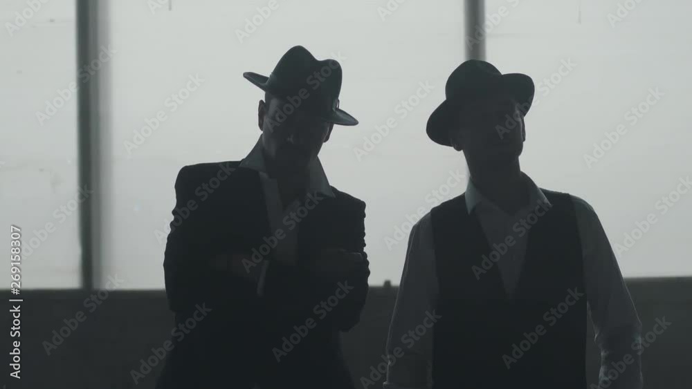 Vidéo Stock Two dark figures of confident well-dressed men in hats ...