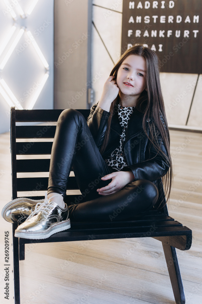Close up portrait of pretty young cute brunette girl sitting on chair ...