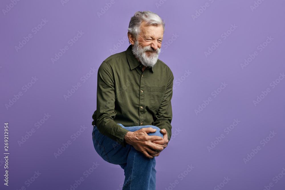 old man suffering from knee pain isolated on blue background. close up ...