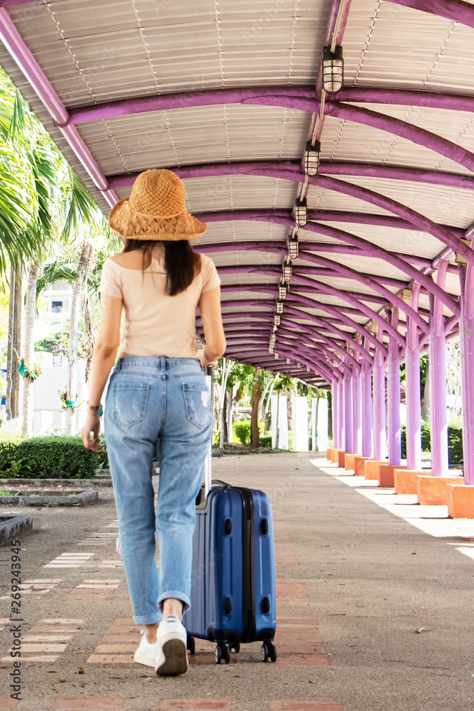 The back side of woman dragging a suitcase with right hand,,walking ...