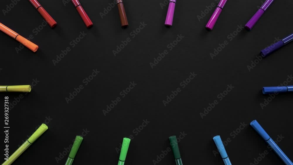 School markers of different colors are located on the black surface ...