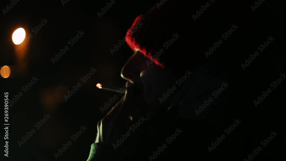 Profile of attractive serious guy smoking a cigarette chilling outside ...