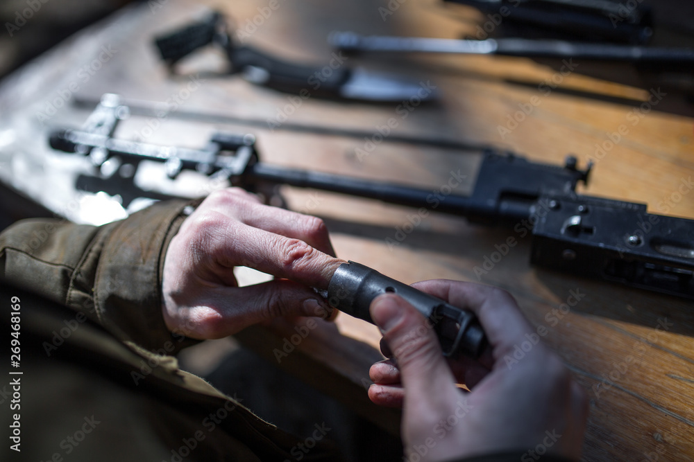 male person soldier cleans the weapon, disassemble, make maintenance of ...